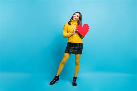 빛나는 사랑스러운 젊은 아가씨의 전체 길이 사진은 빨간 심장 고립 된 파란색 배경을 들고 노란색 스웨터를 착용 갈색 머리에 대한 스톡 사진 및 기타 이미지 Istock