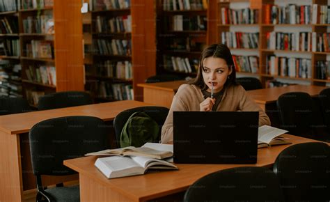 책상에 앉아 종이에 글을 쓰는 여자 사진 Unsplash의 도서관 이미지
