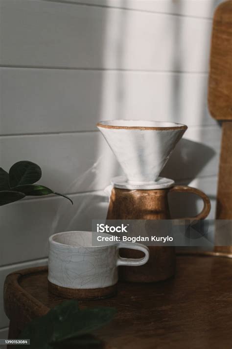 소박한 나무 의자에 햇빛에 커피를 붓고 세련된 햇볕이 잘 드는 방에 그림자를 남기는 현대적인 세라믹 컵 주전자 및 물방울 대체 커피 양조 방법 0명에 대한 스톡 사진 및