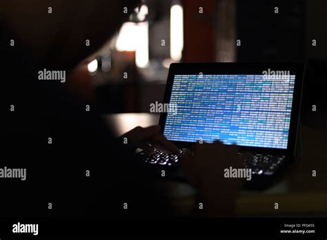 computer hacker silhouette typing on computer in a dark room working