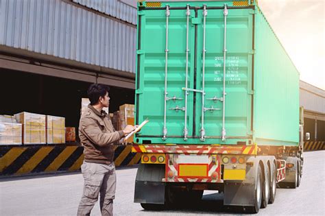 클립보드를 들고 있는 작업자들이 컨테이너 트럭을 검사하고 있다 항구 창고에서 상품 적재를 제어합니다 패키지 상자의 벌크 팔레트 선적 화물 컨테이너 화물 트럭 수출입 물류