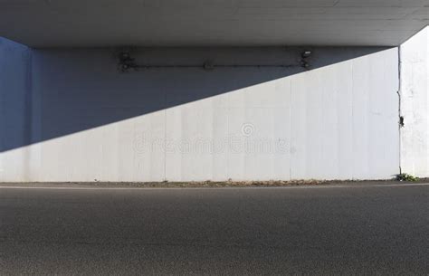 White Concrete Wall Of A Road Underpass Divided In Two By The Shadow Of