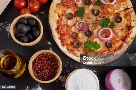 검은 콘크리트 배경에 이탈리아 피자와 피자 요리 재료 포도 나무 모짜렐라 검은 올리브 허브 및 향신료에 토마토 혼합 피자 이탈리아 음식 공간을 복사합니다 맨 위 보기입니다