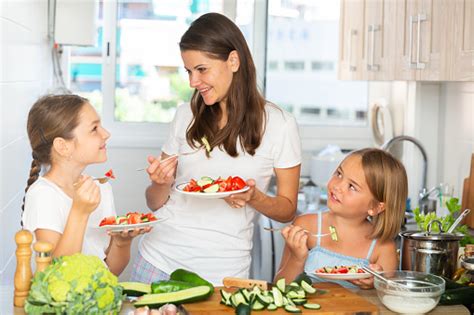 두 어린 딸과 함께 쾌활한 여자는 부엌에서 야채 샐러드를 준비 3 명에 대한 스톡 사진 및 기타 이미지 3 명 30 34세