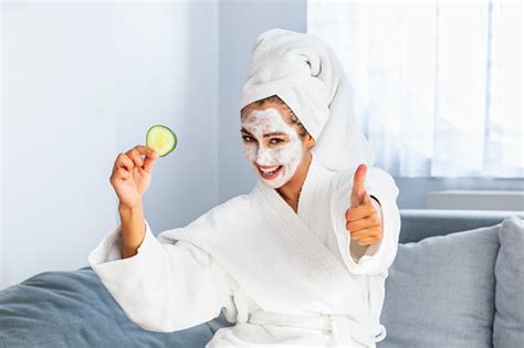 신선한 오이 조각을 들고 그녀의 얼굴에 얼굴 마스크와 아름다운 젊은 여자 스킨 케어 및 트리트먼트 스파 자연의 아름다움과 미용 컨셉 각질제거에 대한 스톡 사진 및 기타