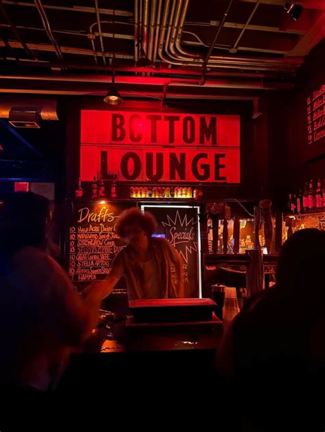 People Are Sitting At A Bar In Front Of A Sign That Reads Bottom Lounge