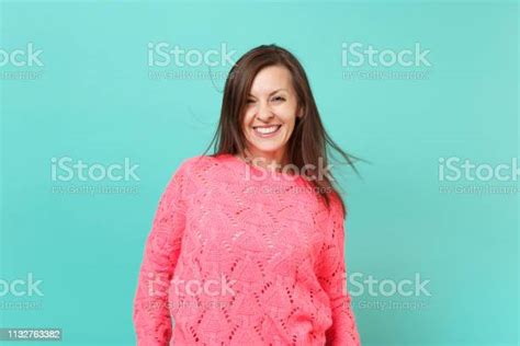 파란색 청록색 벽 배경 스튜디오 초상화에 고립 된 머리를 끼고 있는 니트 핑크 스웨터에 웃는 멋진 젊은 여자 사람들은 진심으로