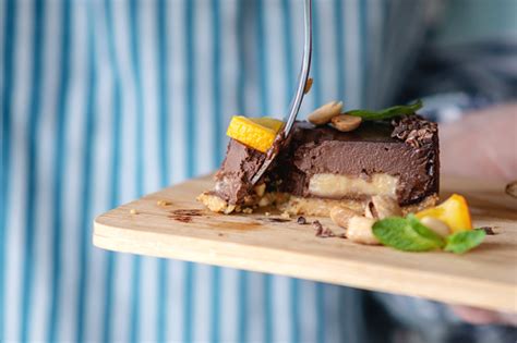 오렌지 민트 잎과 견과류와 초콜릿 케이크의 조각을 포크로 손 나누기 채식주의자를 위한 건강 한 생 디저트 개념에 대한 스톡 사진 및 기타 이미지 Istock