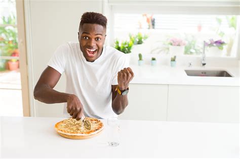 집에서 치즈 피자를 먹는 아프리카계 미국인 남자는 자랑 하 고 승리와 성공을 축 하 하는 것은 매우 흥분 응원 감정 가정 생활에 대한 스톡 사진 및 기타 이미지 Istock