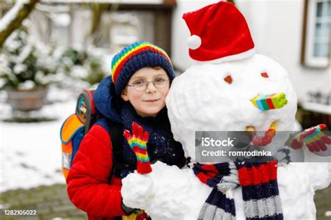 화려한 옷을 입은 어린 학교 소년 초등학교 졸업 후 눈사람과 함께 재미있는 안경과 배낭 남학생에 대한 스톡 사진 및 기타 이미지 남학생 눈 냉동상태의 물 배낭