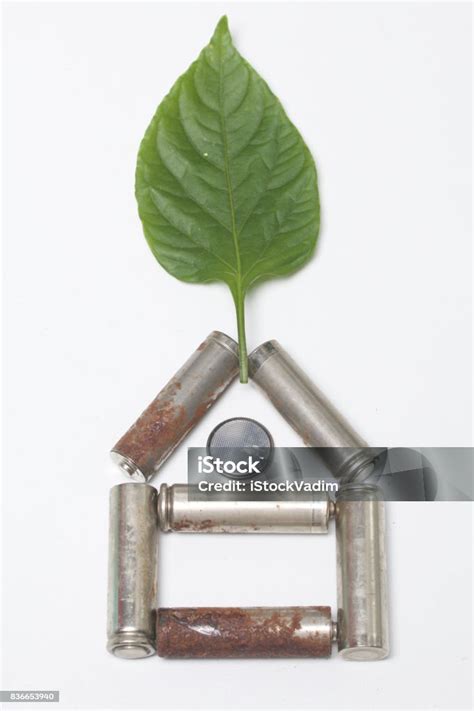 사용한 배터리는 집의 형태로 거짓말 그들 위에 달콤한 녹색 잎이 이다 에 흰색 배경 위에서 볼 수 있습니다 환경 유해 폐기물 처리 삶과 생태의 보호입니다 0명에 대한 스톡