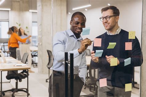 다문화 비즈니스 전문가들이 협업하고 전략 계획 세션 동안 다채로운 스티커 메모와 함께 유리 벽에 아이디어를 공유합니다 20 24세에 대한 스톡 사진 및 기타 이미지 Istock