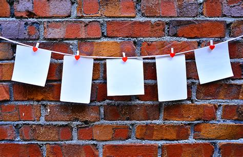 유토이미지 붉은 돌담위에 나란히 걸려있는 사랑그런 하트모양의 집게에 매달린 메모지 5개