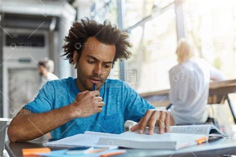 大学高清图片 留着卷发和鬃毛的大学生，在下巴上拿着笔阅读书中重要的内容时，看起来很专注。勤奋的人整天努力学习 教育文化免费下载 格式 编号51385042 千图网