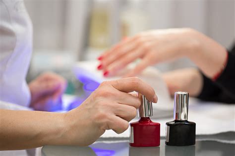 매니큐리스트 마스터는 젊은 여성의 손에 빨간 매니큐어를 만듭니다 뷰티 살롱에서 소녀 고객에게 손톱을 박는 여성 네일 마스터 손 관리 2명에 대한 스톡 사진 및 기타 이미지