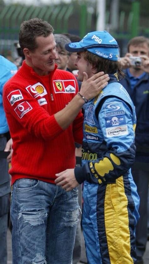 Two Men In Red And Blue Racing Suits Standing Next To Each Other On A