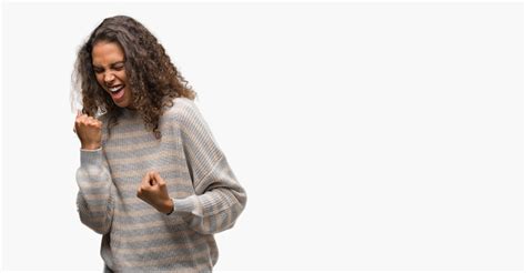 아름 다운 젊은 히스패닉 여자 입고 줄무늬 스웨터 매우 행복 하 고 흥분 무기와 우승자 제스처를 하 고 웃 고 성공을 위한 비명