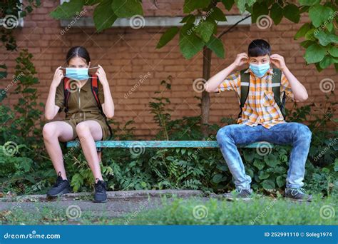 школьники мальчик и девочка подросток сидят на скамейке возле здания школы они используют