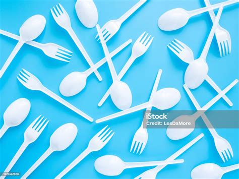 일회용 식기 흰색 플라스틱 포크와 숟가락은 파란색 배경 상단보기 평평한 평신도에 흩어져 있습니다 플라스틱 제품의 생태 및