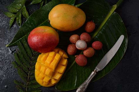 접시에 얇게 썬 망고 덩어리가 있는 신선한 망고 과일과 어두운 배경에 붉은 피부와 흰 살을 보여주는 신선하고 껍질을 벗긴 열매 건강한 식생활에 대한 스톡 사진 및 기타