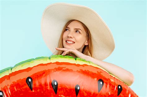 수영복을 입은 여름 모자를 쓴 아름다운 소녀가 고립된 파란색 배경에 풍선 반지를 끼고 서 있습니다 공기 주입에 대한 스톡 사진 및 기타 이미지 Istock