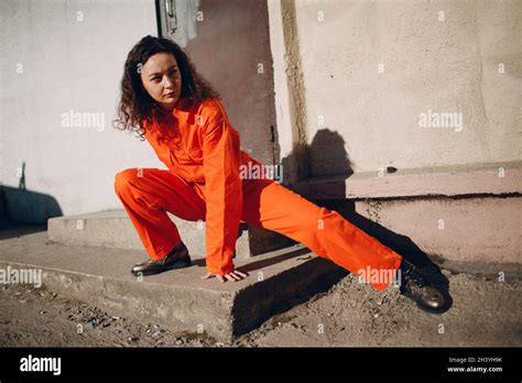 Young Brunette Curly Woman In Orange Suit Female In Colorful Overalls