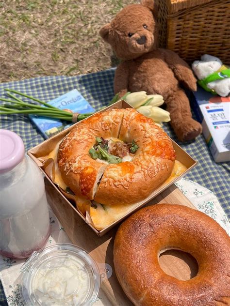A Picnic Table With Two Bagels Yogurt And A Teddy Bear