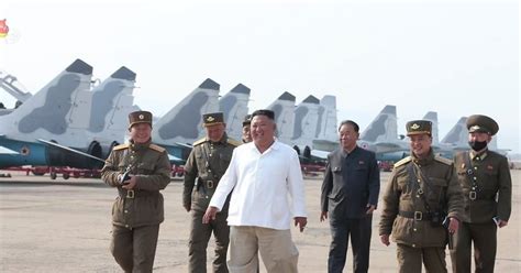 김정은 전투기 뒤로하며 만족스러운 얼굴