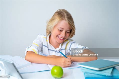 책상에 앉아 웃고 있는 중학교 소년 소녀 교실에서 글쓰기 책과 태블릿을 공부하고 있다 학교로 돌아 가기 어린 시절 교육 어린이를위한 제품 10 11세에 대한 스톡 사진 및