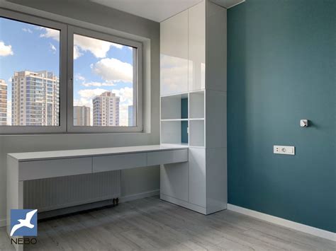 Белый узкий письменный стол со встроенным распашным шкафом и полками у окна на заказ в Москве