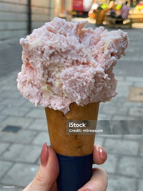 화끈한 날에 는 도시 거리를 걷고 와플을 들고 있는 인식할 수 없는 사람들의 클로즈업 이미지 화이트 초콜릿과 라즈베리 젤라토를 곁들인 아이스크림 콘 전경에 집중 거리에 대한