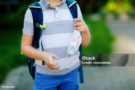 의료 용 마스크와 배낭 이나 가방 아이 소년의 클로즈업 학교에 가는 길에 학교 키드 야외에서 아이 코로나 전염병 잠금에서 격리 시간 후 학교로 돌아갑니다 얼굴이 없습니다
