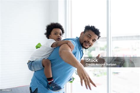 행복한 아프리카계 미국인 아버지 돼지 백 귀여운 곱슬 작은 아들 쾌활한 아프리카 아빠 놀이 재미와 집에서 작은 아들과 함께 시간을 보내고 2 3 살에 대한 스톡 사진 및