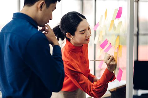 두 명의 캐주얼 비즈니스 사람들이 현대 사무실의 유리 창에 스티커 메모와 함께 프로젝트를 통해 작성하고 브레인 스토밍 팀워크 컨셉 20 24세에 대한 스톡 사진 및 기타