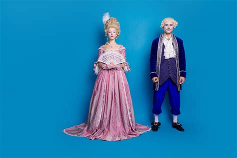 눈에 띄는 파란색 배경에 화려한 바로크 의상을 입고 역사적인 요소와 현대적인 요소가 조화를 이루는 우아한 커플 16 17 살에