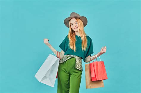 쇼핑백을 들고 있는 행복한 젊은 여성 예쁜 소녀 산책 쇼핑 센터는 파란색 배경에 좋은 많은 팩을 수행 14 15 살에 대한 스톡