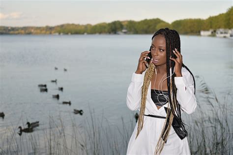 긴 검은 색과 금발 머리띠와 아프로 스타일의 검은 소녀는 배경에 호수와 헤드폰전화로 이야기 땋은 머리에 대한 스톡 사진 및 기타