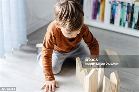 작은 백인 소년 작은 아이 Ar 홈 아이의 전체 길이보기 는 나무 또는 비닐 적층 바닥에 앉아 집의 모양으로 나무 장난감 벽돌로 재생 혼자 개발 창의력 탑 보기 가정 생활에