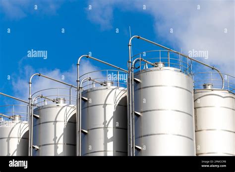 Stainless Steel Silos Against The Blue Sky Warehouses For Storage Of Plastics And Bulk Grains