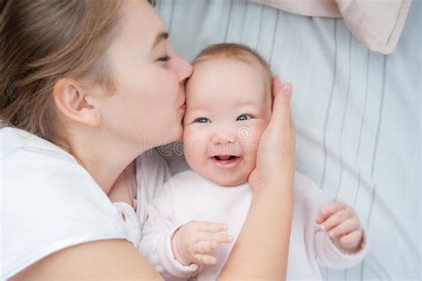Madre Besando A Su Bebé En Cama La Madre Feliz Besa A Un Bebé En La