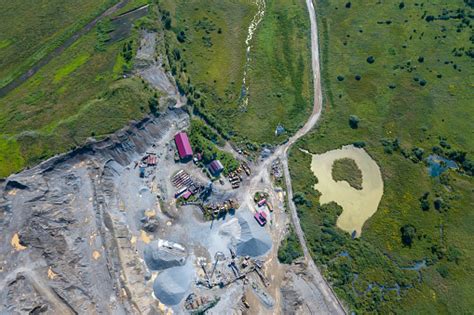 건축 자재의 더미 근처 생산 및 청소 잔해와 시멘트에 대한 작은 공장의 공중 보기 트랙터와 트럭은 완성 된 제품을 수송한다 채석장에서 채광 건설 산업에 대한 스톡 사진 및