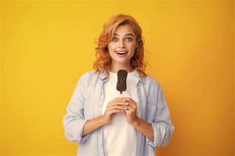 Young Woman Eat Ice Creams With Chocolate Glaze On Yellow Background
