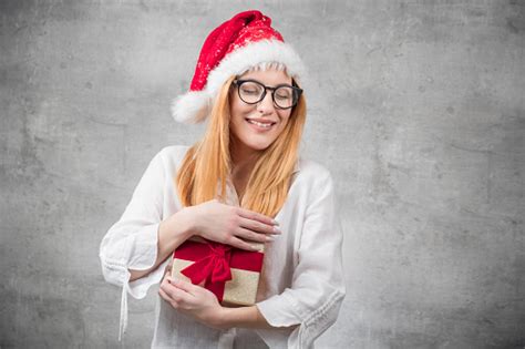 회색 배경에 고립 된 크리스마스 선물과 즐거움 산타 여자 기쁘게 어린 소녀 입고 빨간 산타 모자와 들고 선물 상자 20 24세에 대한 스톡 사진 및 기타 이미지 Istock