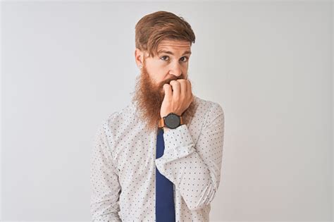 젊은 빨간 머리 아일랜드어 사업가 는 손톱을 물고 입에 손을 긴장 찾고 고립 된 흰색 배경 위에 서 불안 문제 감정에 대한 스톡