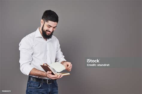 흰색 셔츠를 입고와 오픈 도우미 페이지를 꺼내서 들고 수염된 젊은 남자의 초상화 회색 벽 배경 경영자에 대한 스톡 사진 및 기타 이미지 Istock