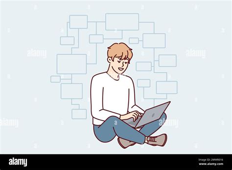 Young Man Programmer Sits Cross Legged On Floor With Laptop On Lap And Creates Web Application
