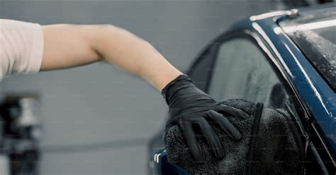 현대 세차 서비스에서 극세사 천과 청소 자동차 거울을 들고 검은 고무 장갑을 낀 남성 손을 닫습니다 사진 Unsplash의