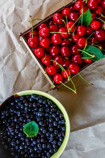 블루베리와 상자의 자른 그릇 공예 주름 오래된 종이 배경에 꼬리와 빨간 달콤한 체리의 크레이프 세로 유기농 식품 맨 위 보기입니다 여름 과일과 열매 단호하게 정물 빌베리