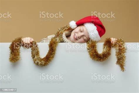 당신이 당신의 텍스트를 배치 할 수있는 흰색 빌보드와 산타 모자에 졸린 빨간 머리 소녀 크리스마스와 새해를 위한 광고 컨셉 10 11세에 대한 스톡 사진 및 기타 이미지