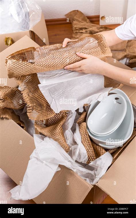 Detail Of Woman Packaging Fragile Items Using Crumpled Packing Paper Concept Of Moving In Or
